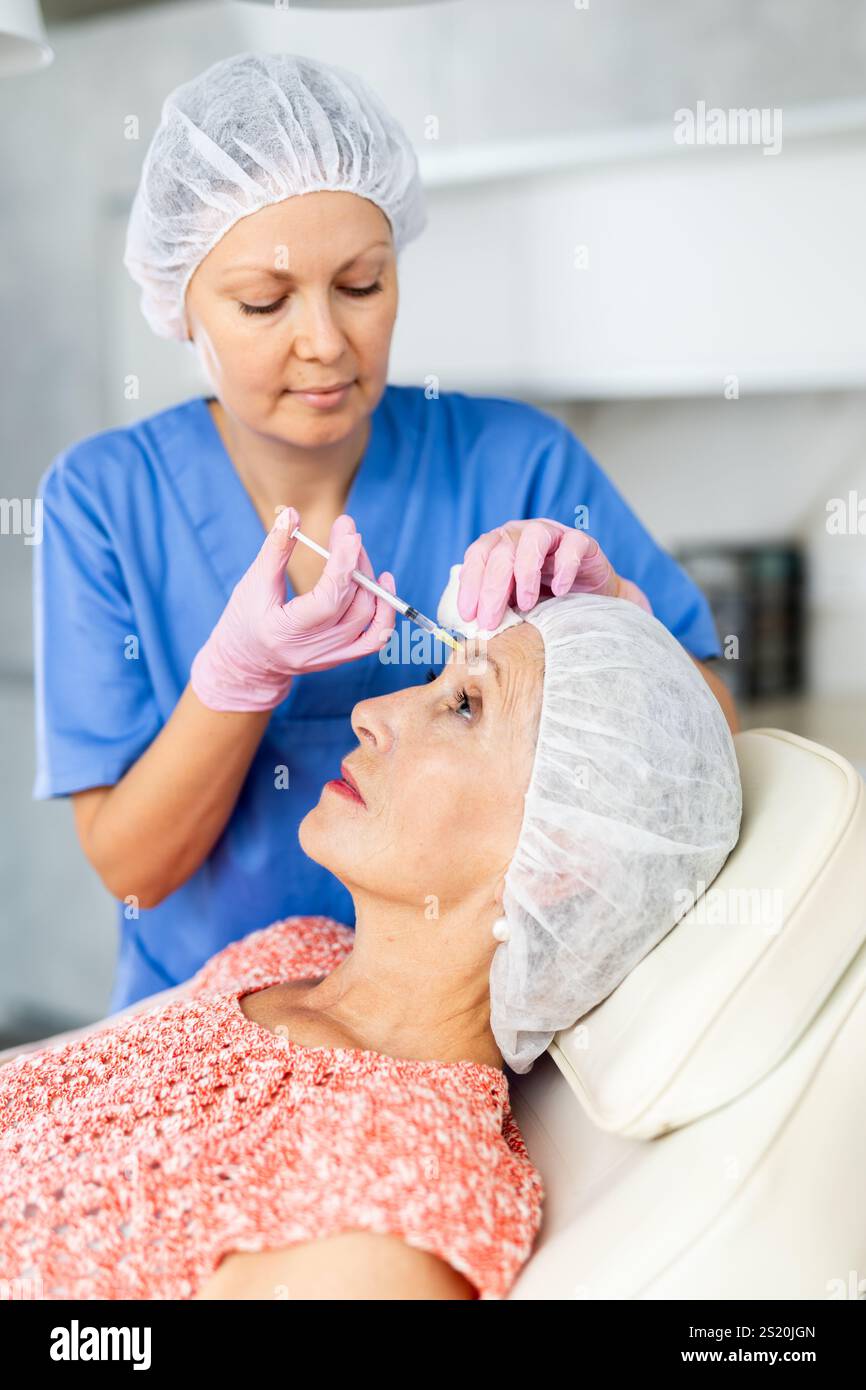 Adult female doctor makes injection in forehead of female patient Stock ...