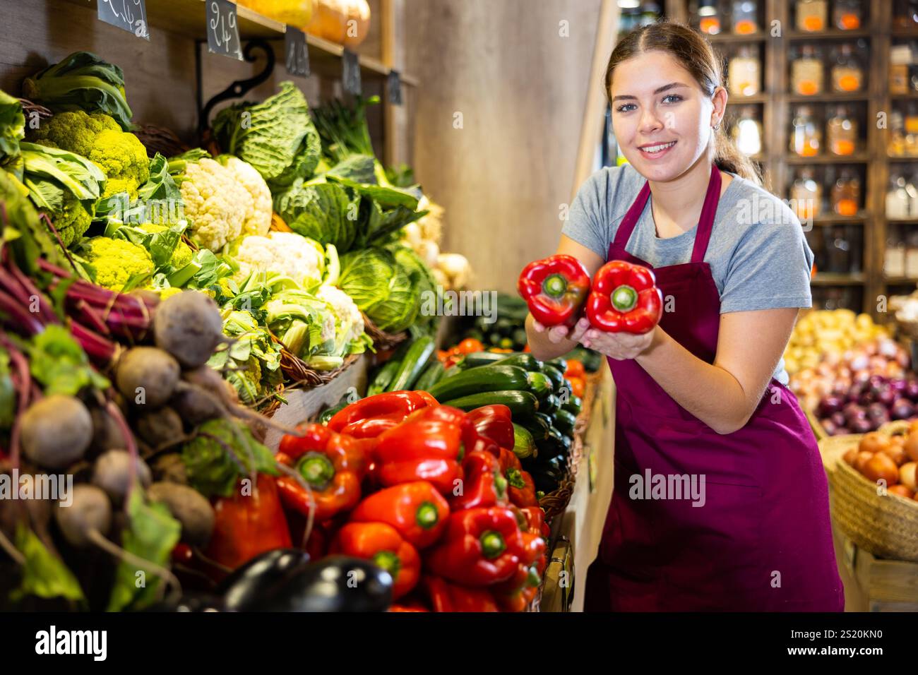 Female grocery store worker lays out bell peppers on the counter and ...