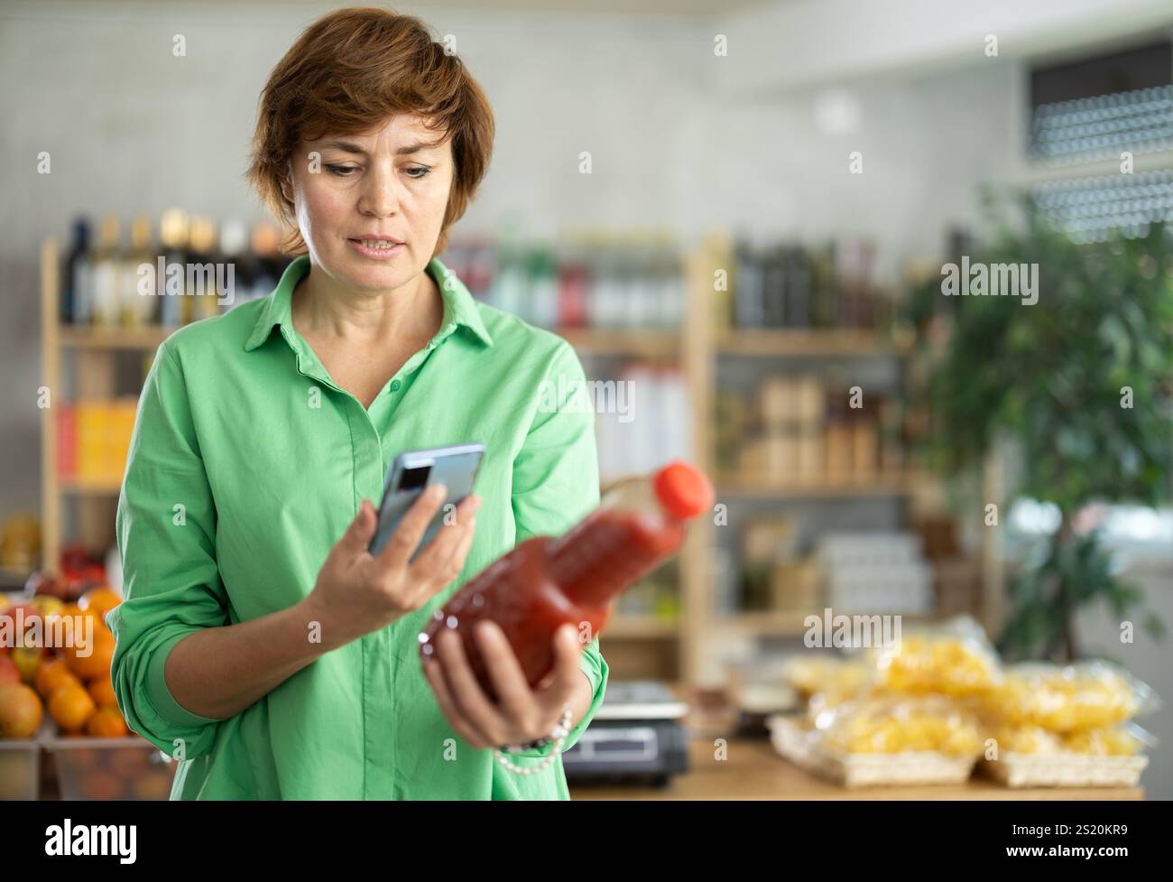 Woman scanning QR code on bottle tomato juice label in grocery ...