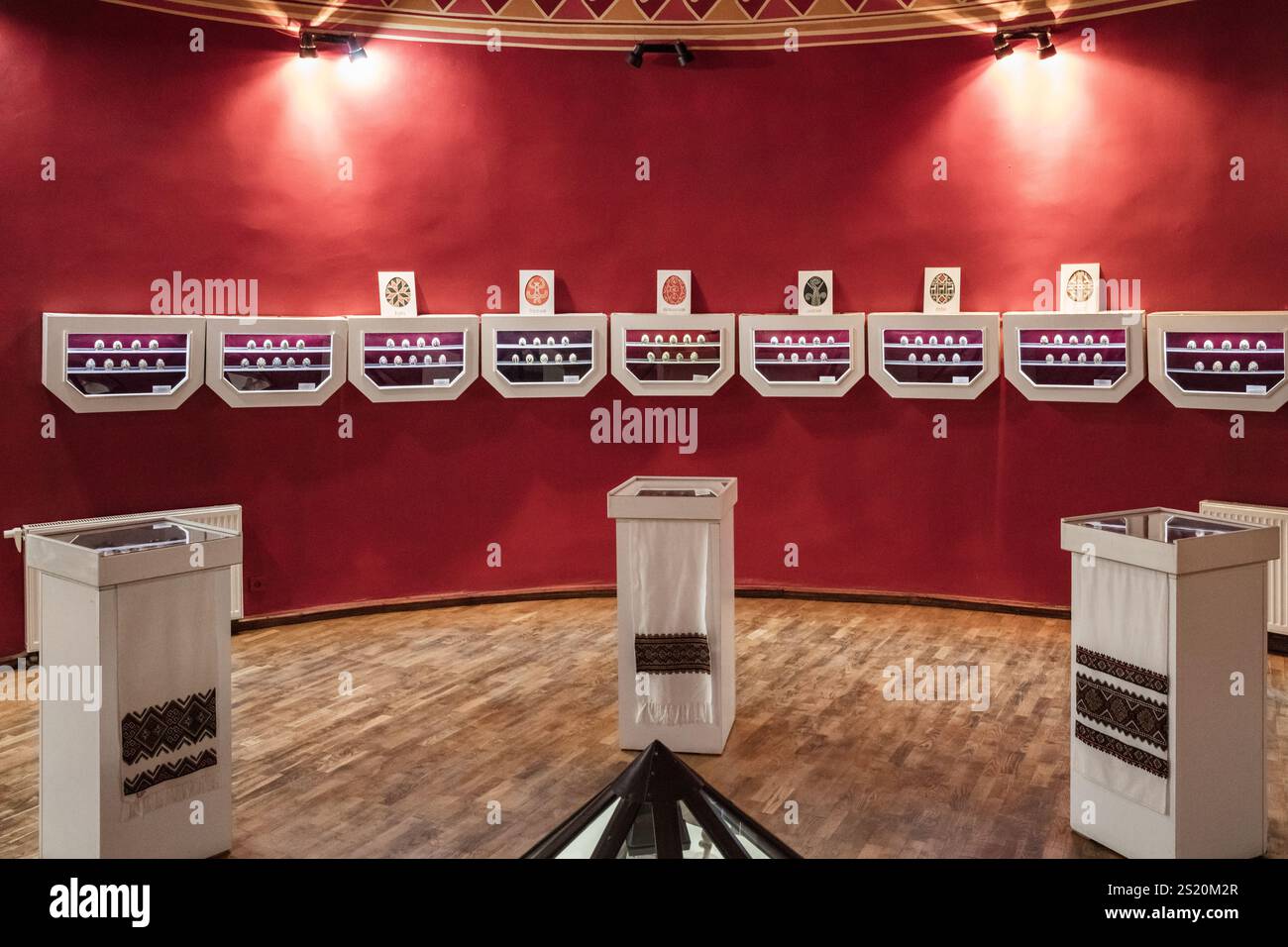 A room with many display cases and a few pedestals. The room is red and ...