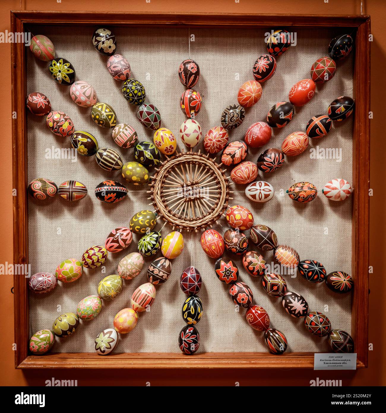A display of colorful eggs in a wooden box. The eggs are arranged in a ...