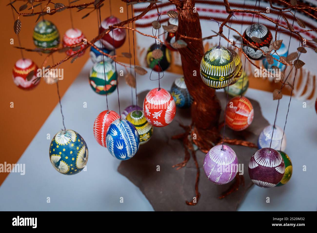 A tree with many colorful eggs hanging from it. The eggs are of ...