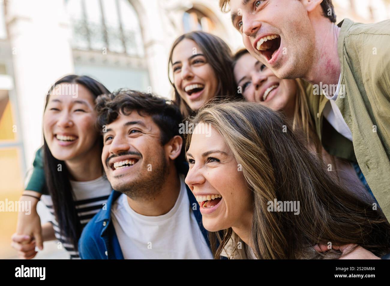 Happy group of young students hugging each other laughing outdoors ...