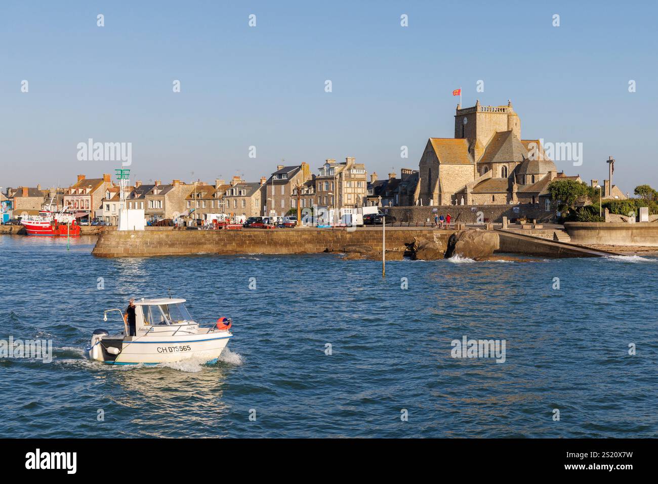 Boat leaving harbour in front of church, Barfleur, Manche, Normandy ...