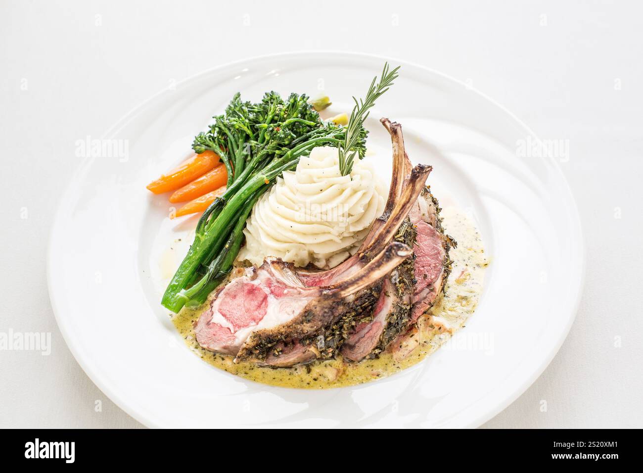 A plate of lamb chops with mashed potatoes and vegetables. The lamb ...