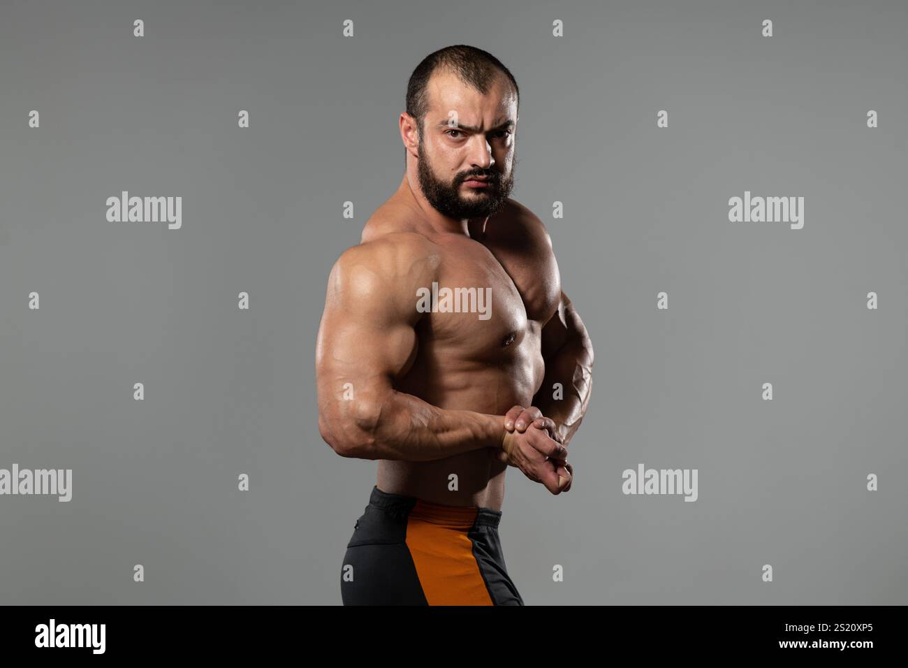 Man Flexing Muscles In Studio With Grey Background Stock Photo - Alamy