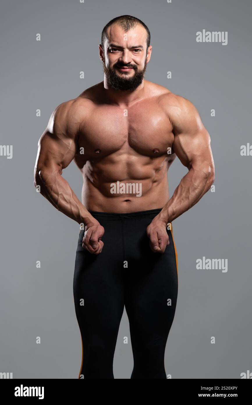 Man Flexing Muscles In Studio With Grey Background Stock Photo - Alamy