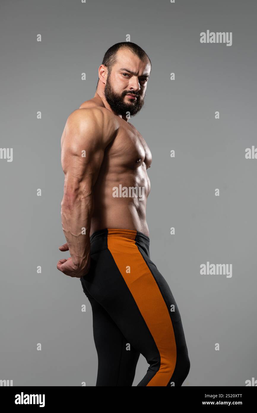 Man Flexing Muscles In Studio With Grey Background Stock Photo - Alamy