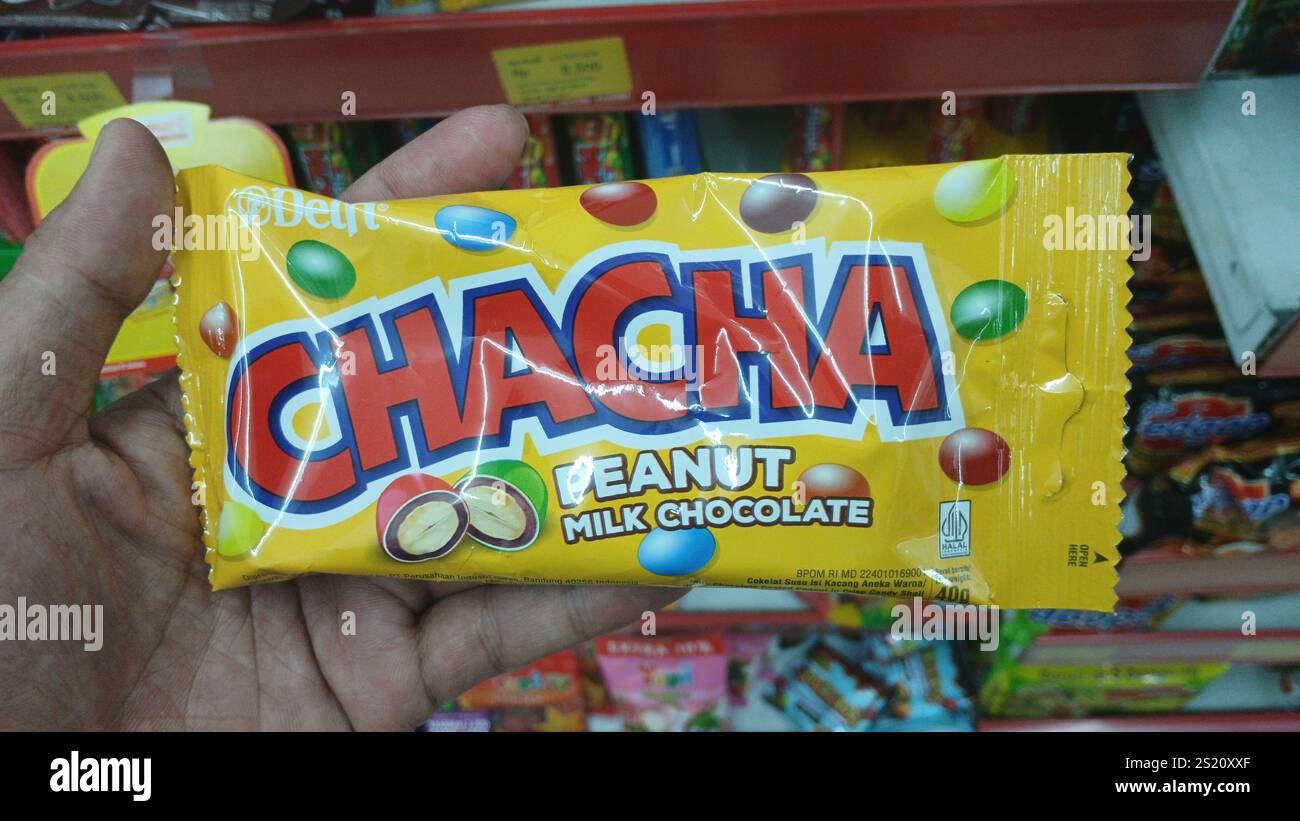 Hand holding Cha cha snack. Cha cha is peanut with milk chocolate which ...