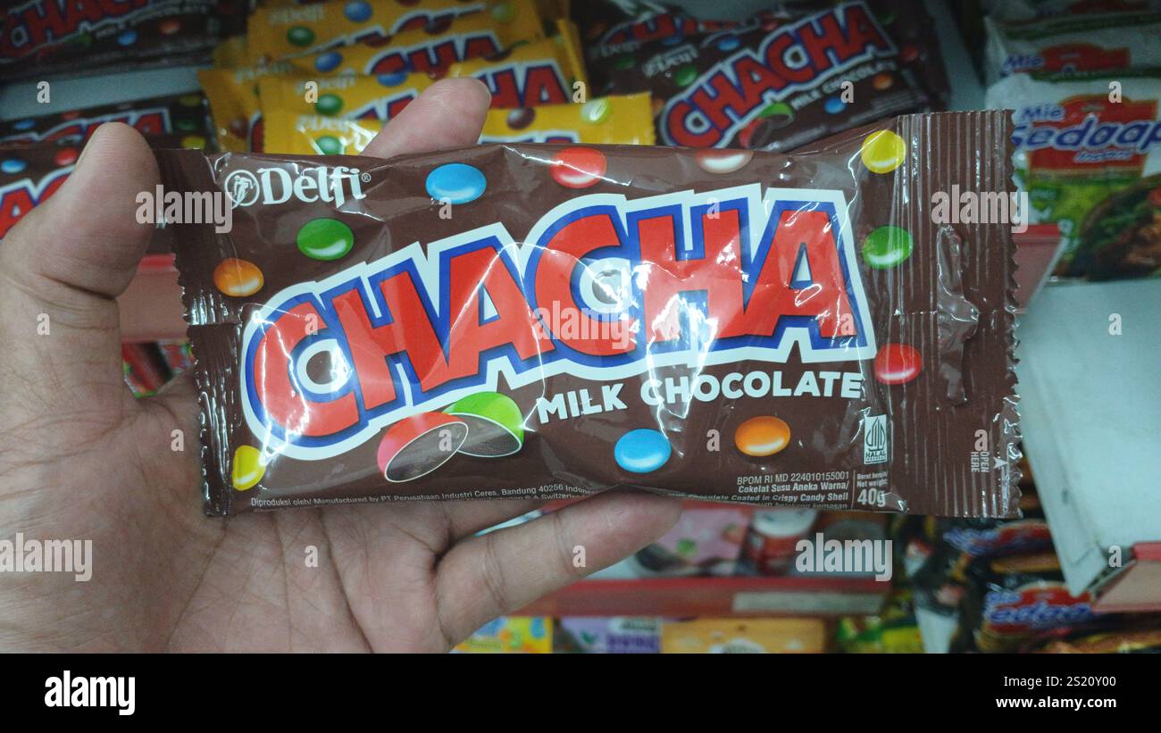 Hand holding Cha cha snack. Cha cha is peanut with milk chocolate which ...