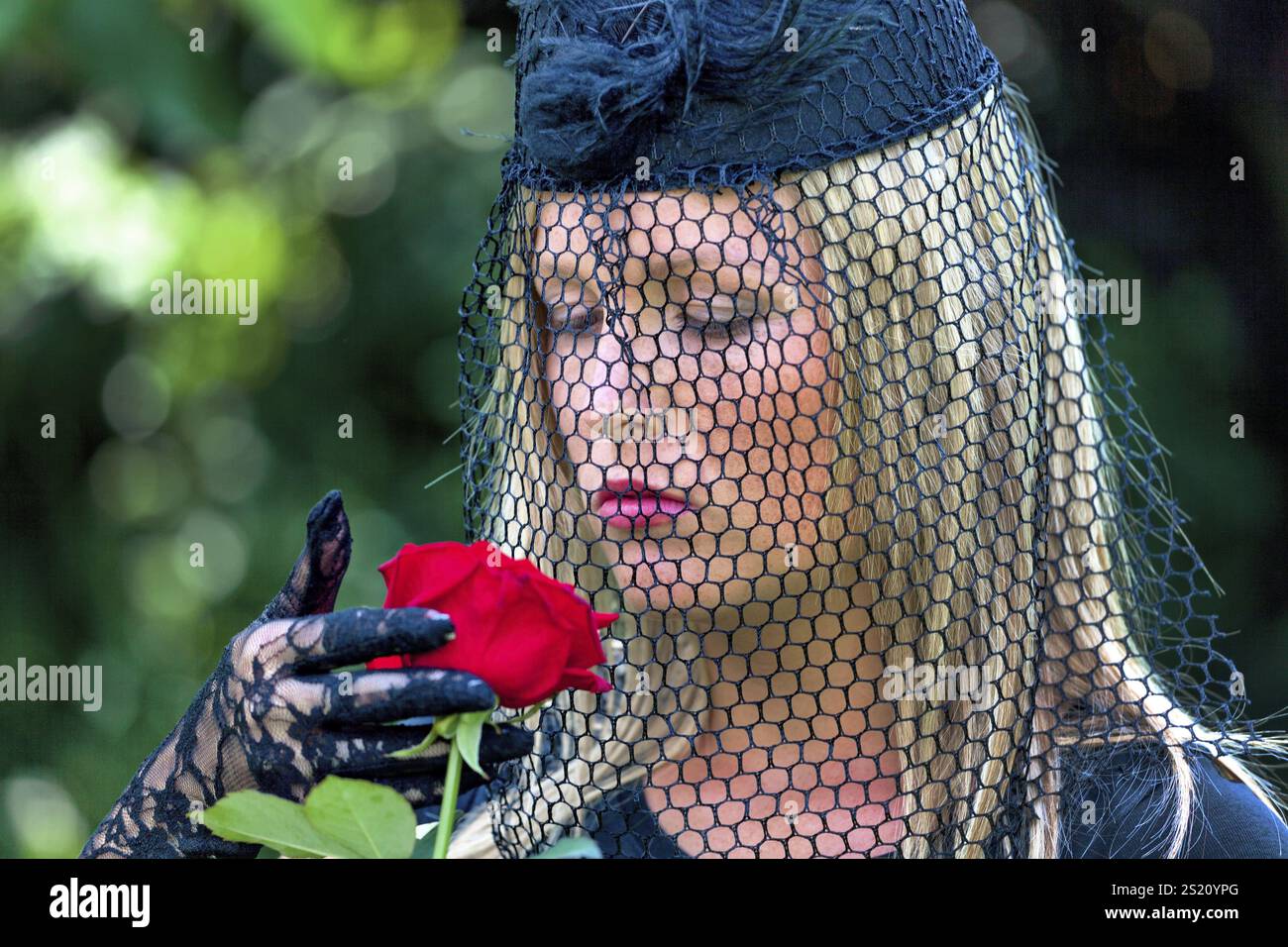 A young widow in a cemetery with a red rose shows mourning Stock Photo ...