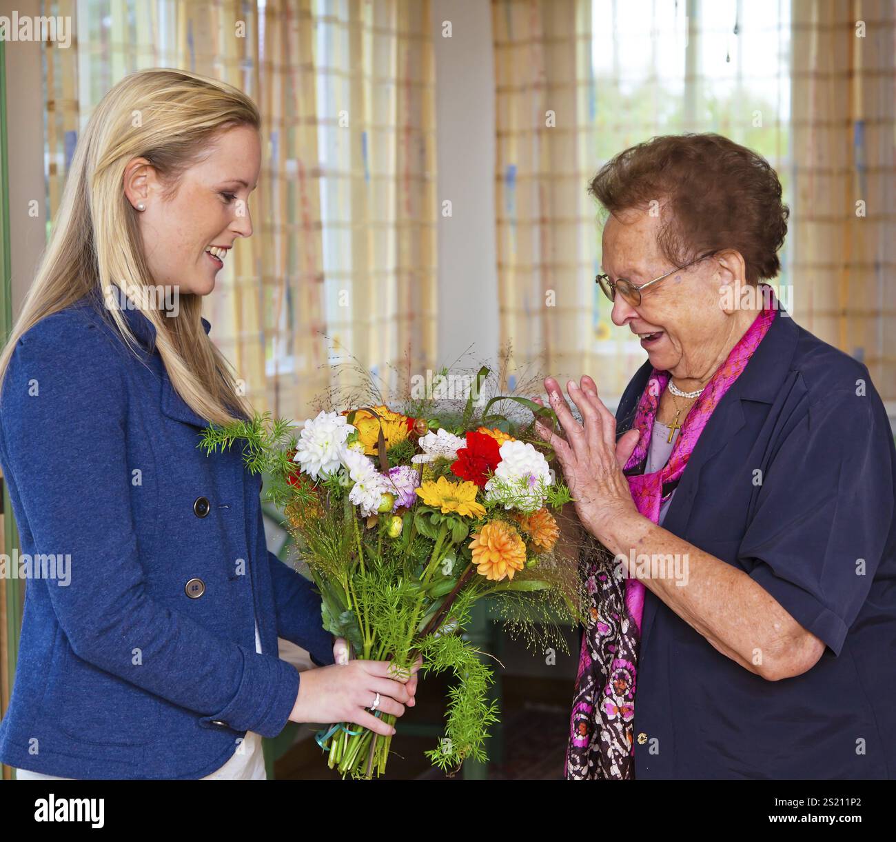 A grandson visits his grandmother and brings flowers as a gift. Austria ...