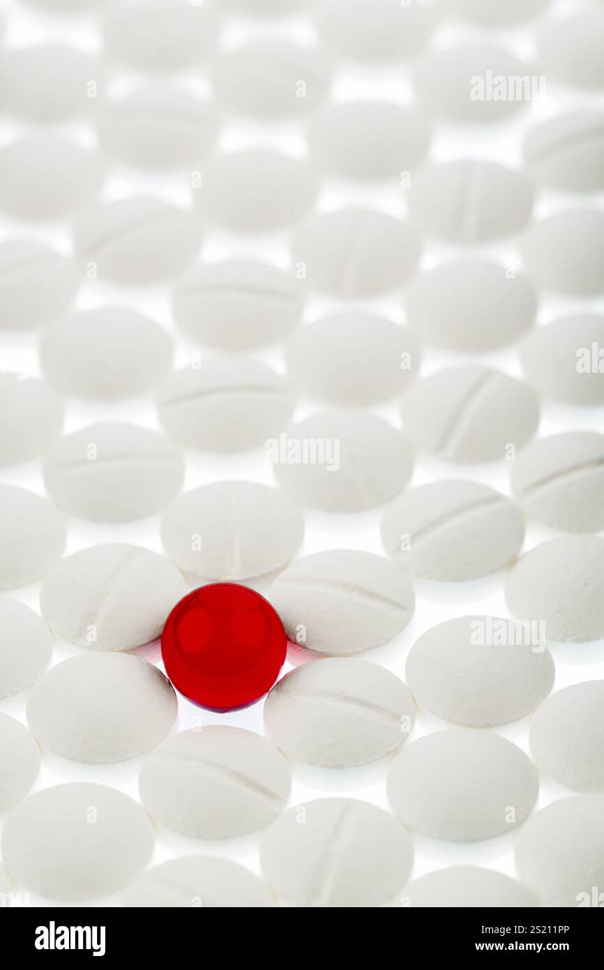 White tablets in contrast with a red tablet, symbolic photo for ...