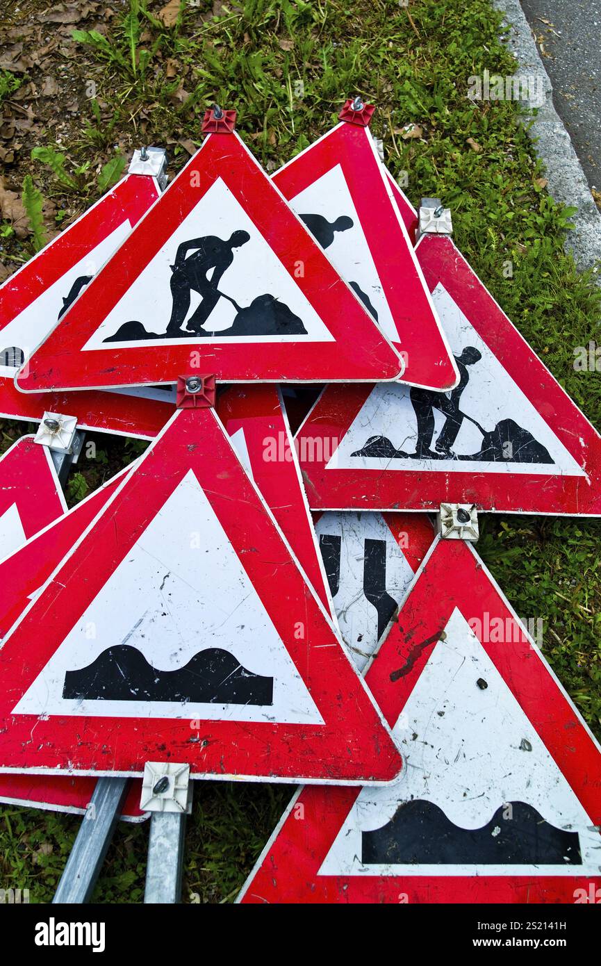 Many traffic signs at a roadworks site lie on top of each other on the ...