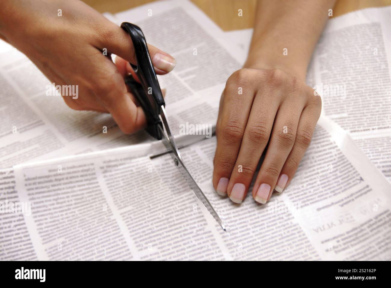 Hand with scissors cutting out an article from a newspaper Stock Photo ...