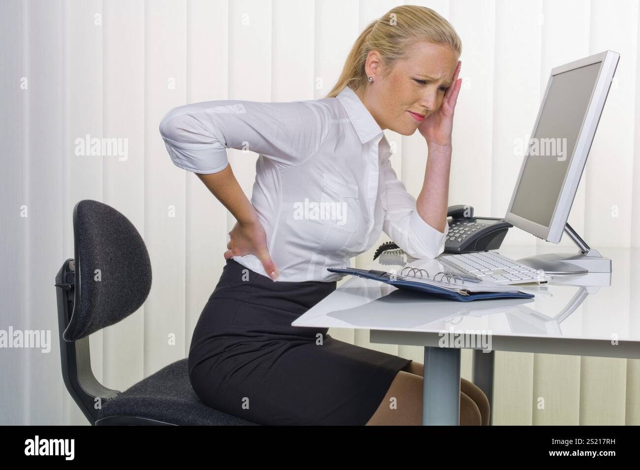 A woman with back pain from sitting for long periods in the office ...