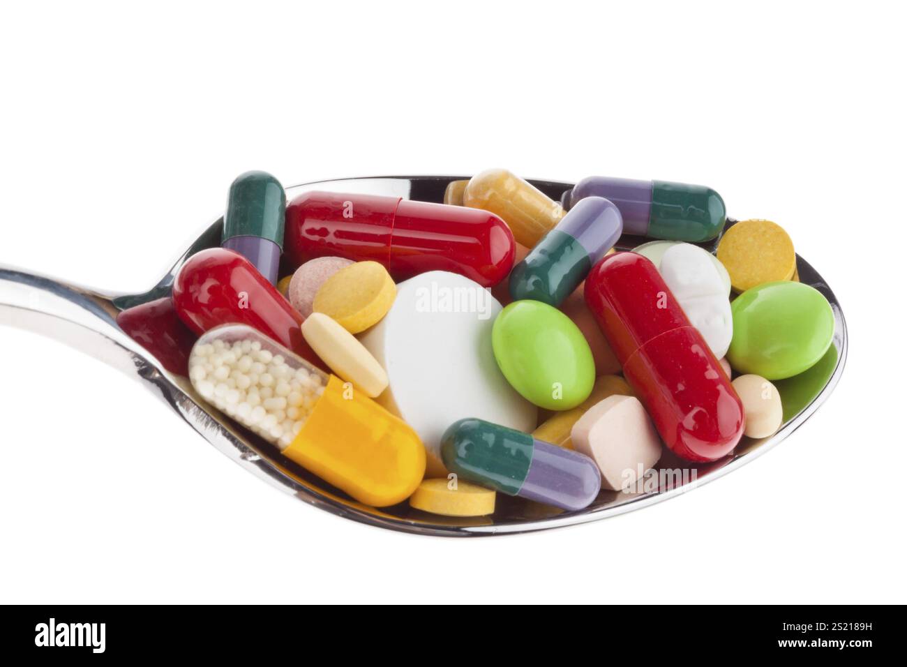 Many different coloured tablets on a spoon. Abuse of medication ...