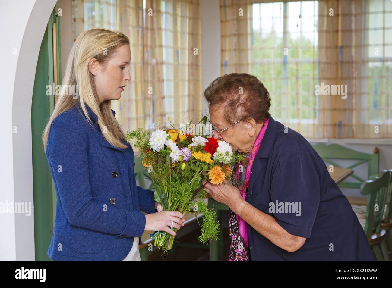 A grandson visits his grandmother and brings flowers as a gift. Austria ...