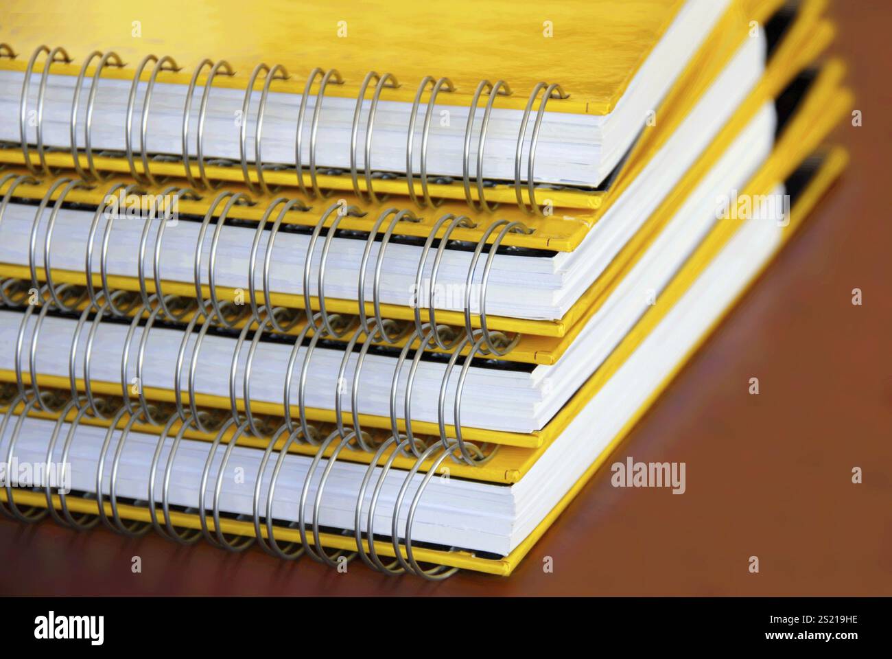 Four yellow ring-bound notebooks piled up on the desk, close-up Stock ...