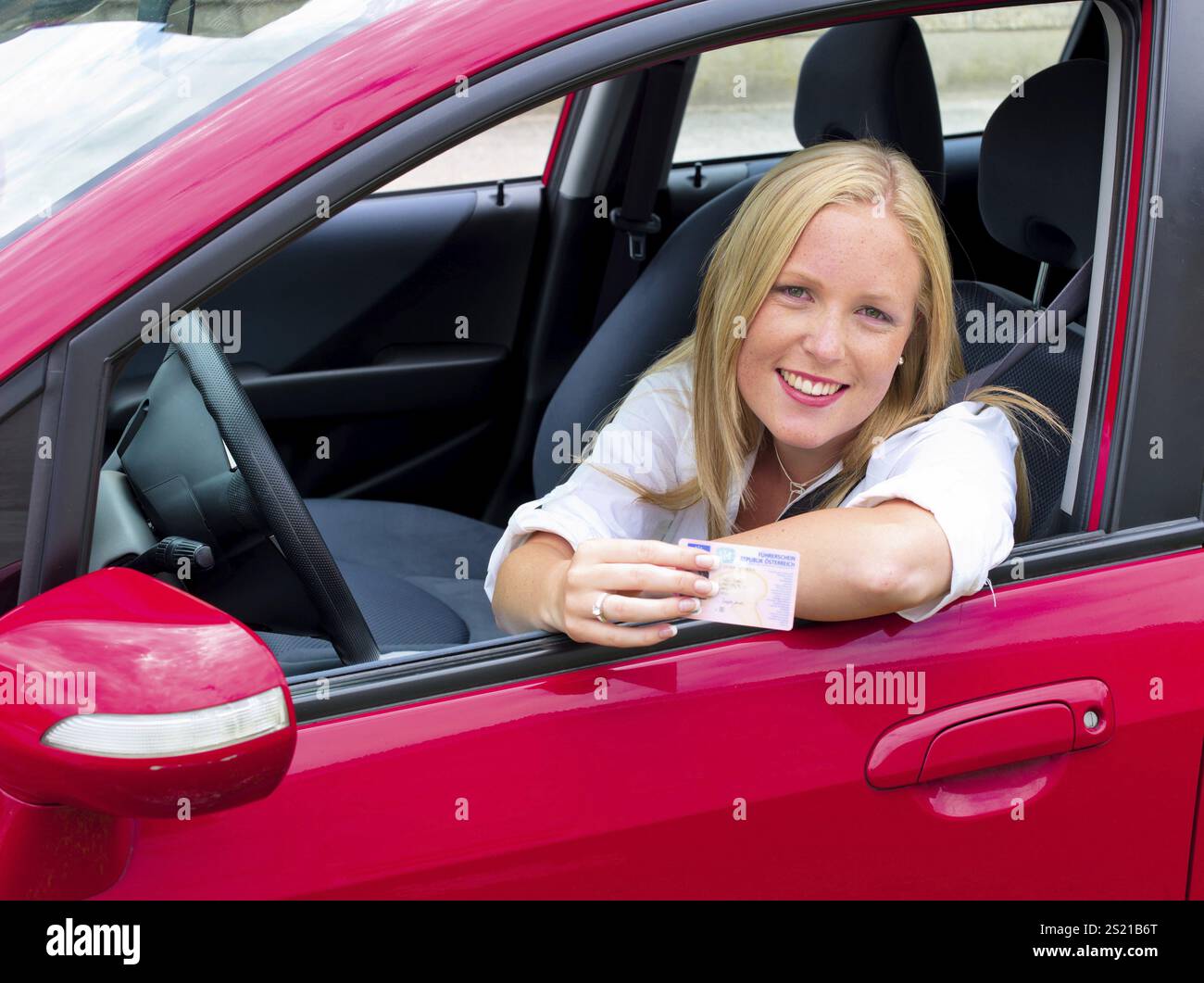 A young woman proudly shows off her driving licence. Driving licence ...