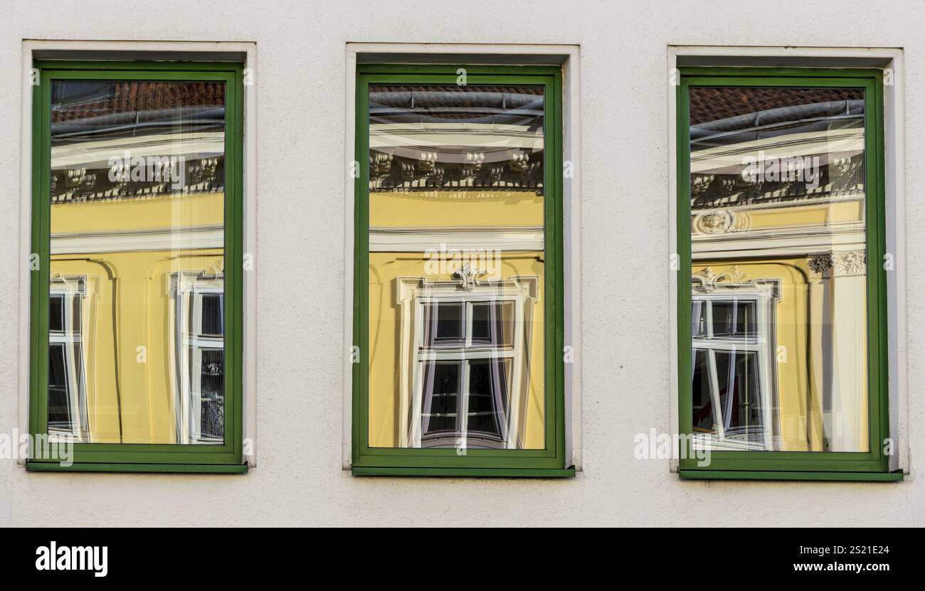 A refurbished residential building is reflected in the modern window of ...