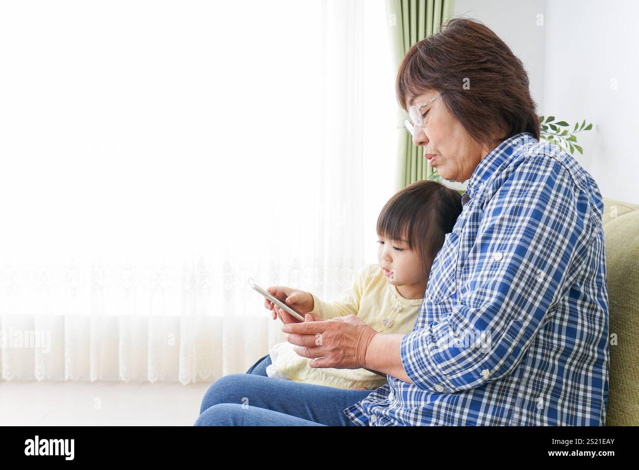 Child using a phone with grandma Stock Photo - Alamy