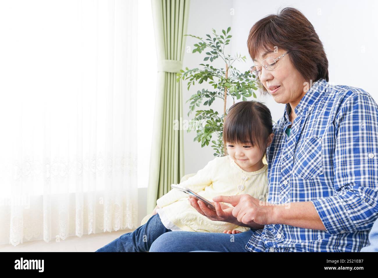 Child using a phone with grandma Stock Photo - Alamy