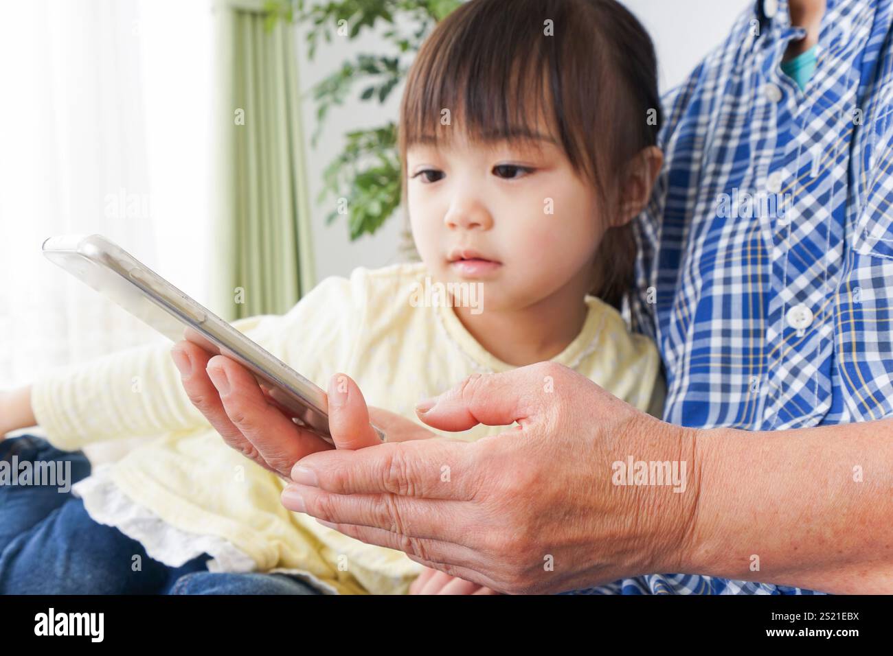 Child using a phone with grandma Stock Photo - Alamy
