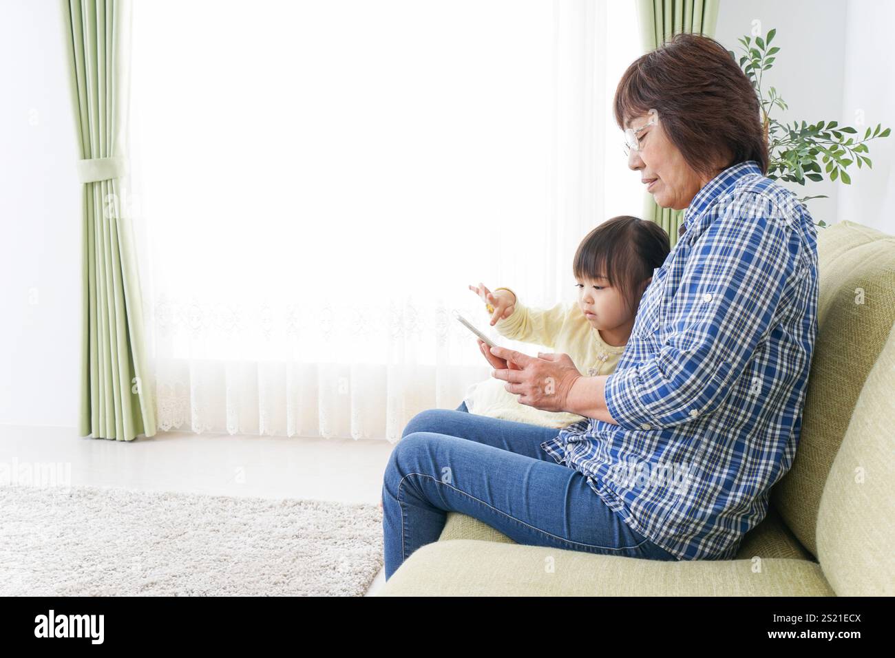 Child using a phone with grandma Stock Photo - Alamy