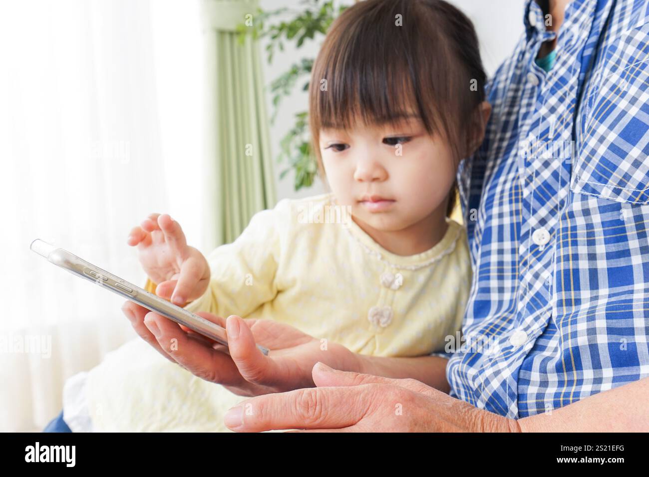 Child using a phone with grandma Stock Photo - Alamy