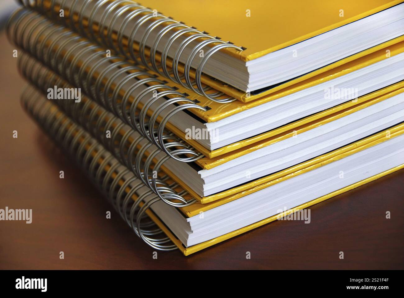Four yellow ring-bound notebooks piled up on the desk, close-up Stock ...