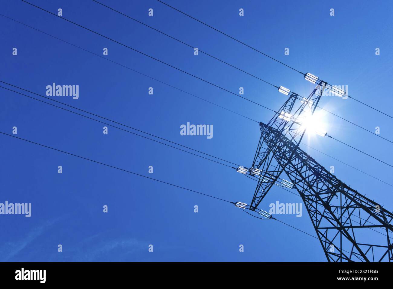 The pylon of a high-voltage power line with sun and blue sky. Energy ...