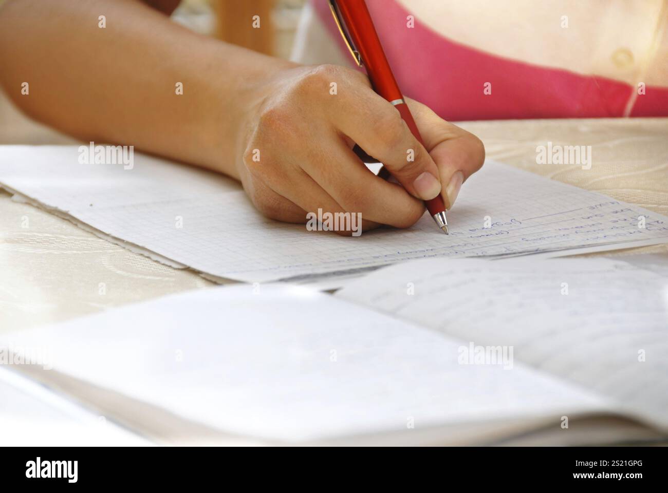 Schoolgirl with pencil writing down homework in exercise book Stock ...