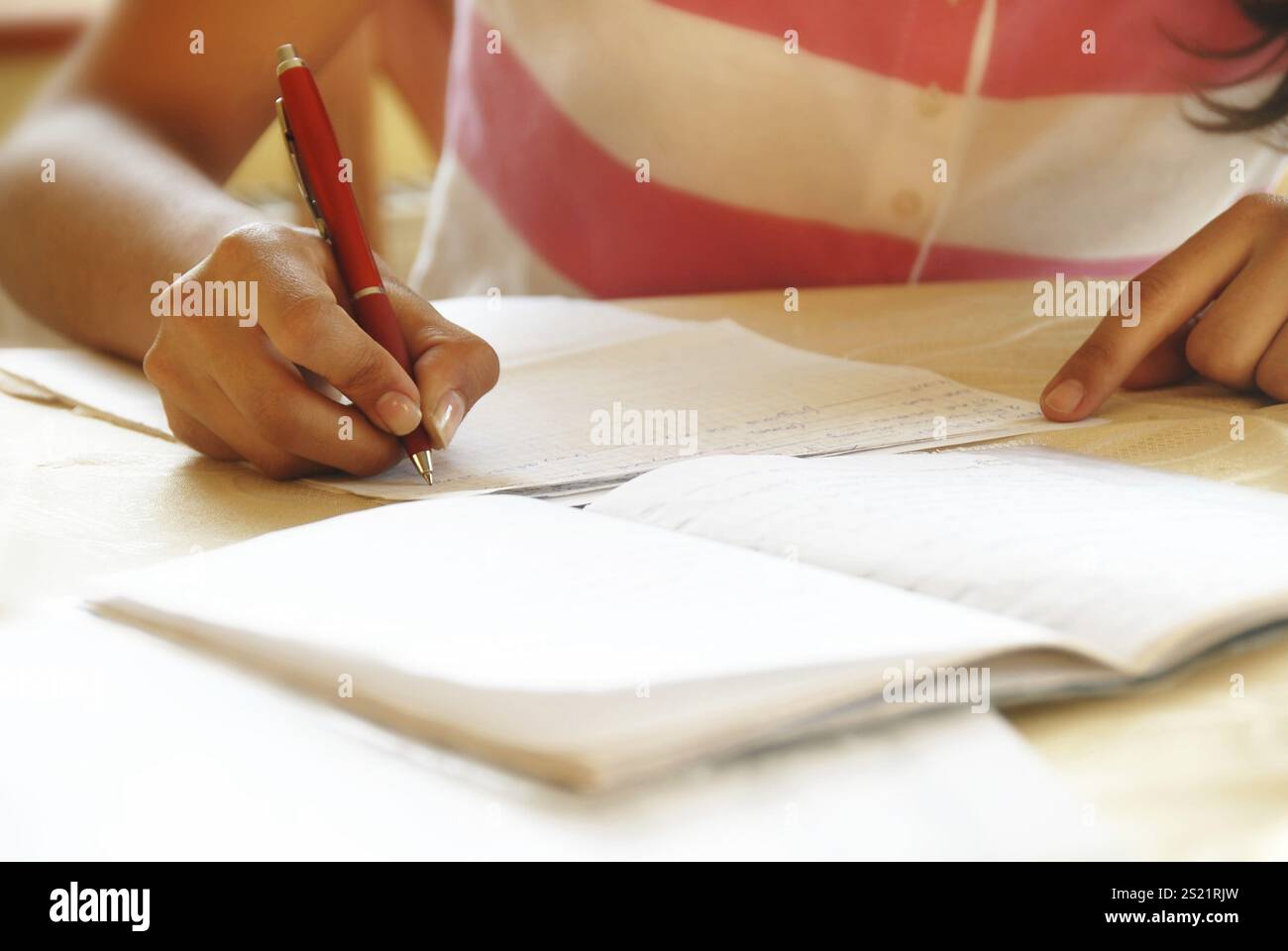 Schoolgirl with pencil writing down homework in exercise book Stock ...