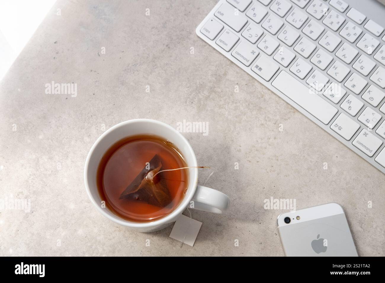 Keyboard, tea and phone on grey table Stock Photo - Alamy