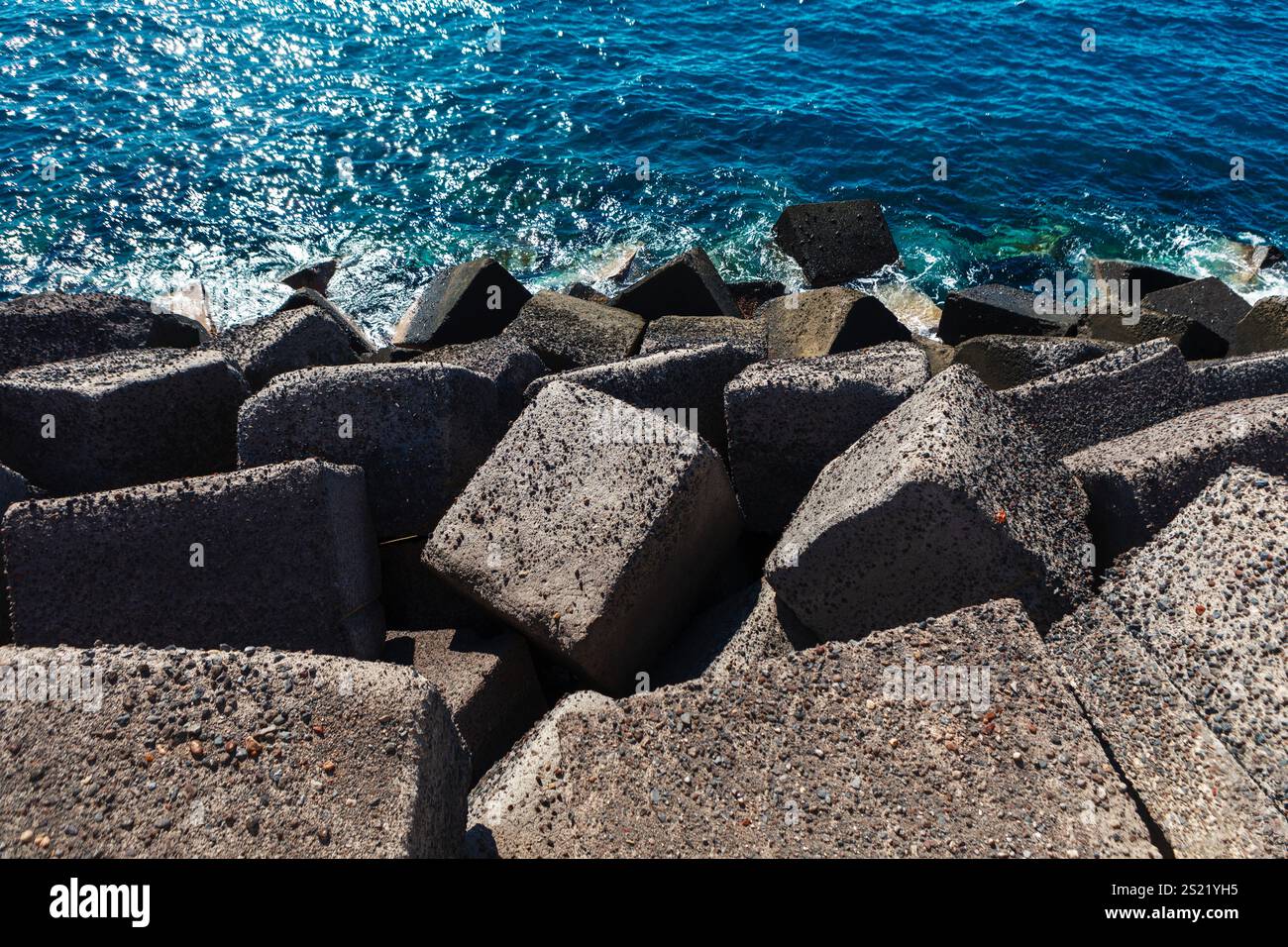 Shaped concrete blocks arranged along shoreline, with ocean water ...