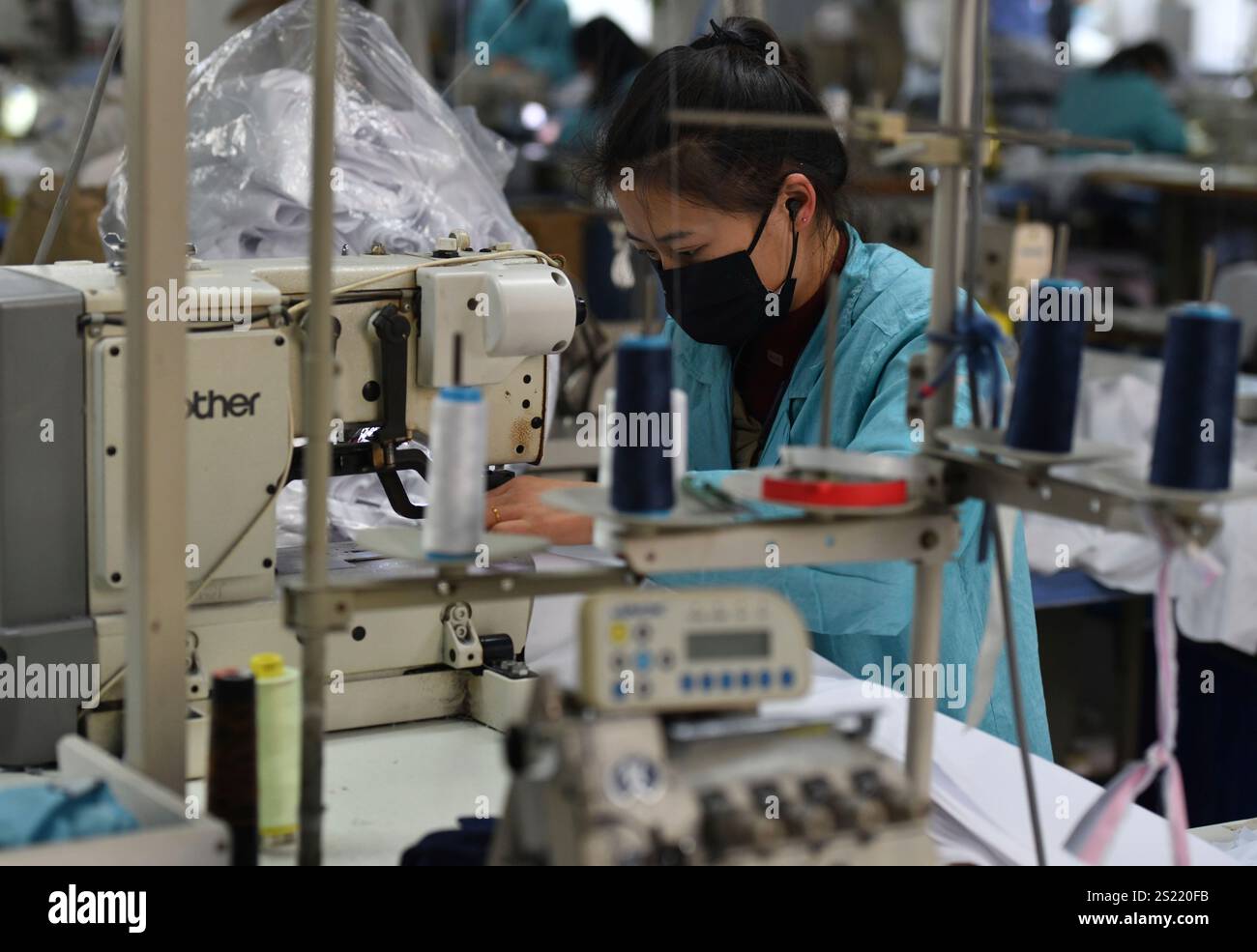 A woman works on the production line of shirts at a textile ...