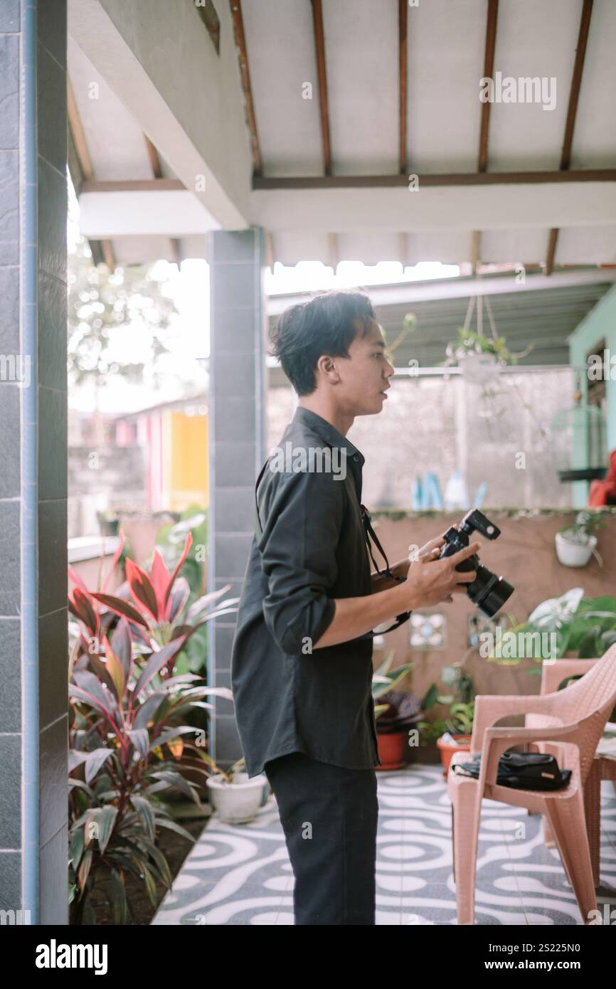 An Asian man holding a camera, poised to capture a photo of something ...