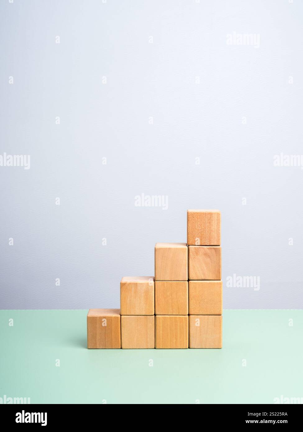 Wooden cube blocks arranged as bar graph chart steps on green table and ...