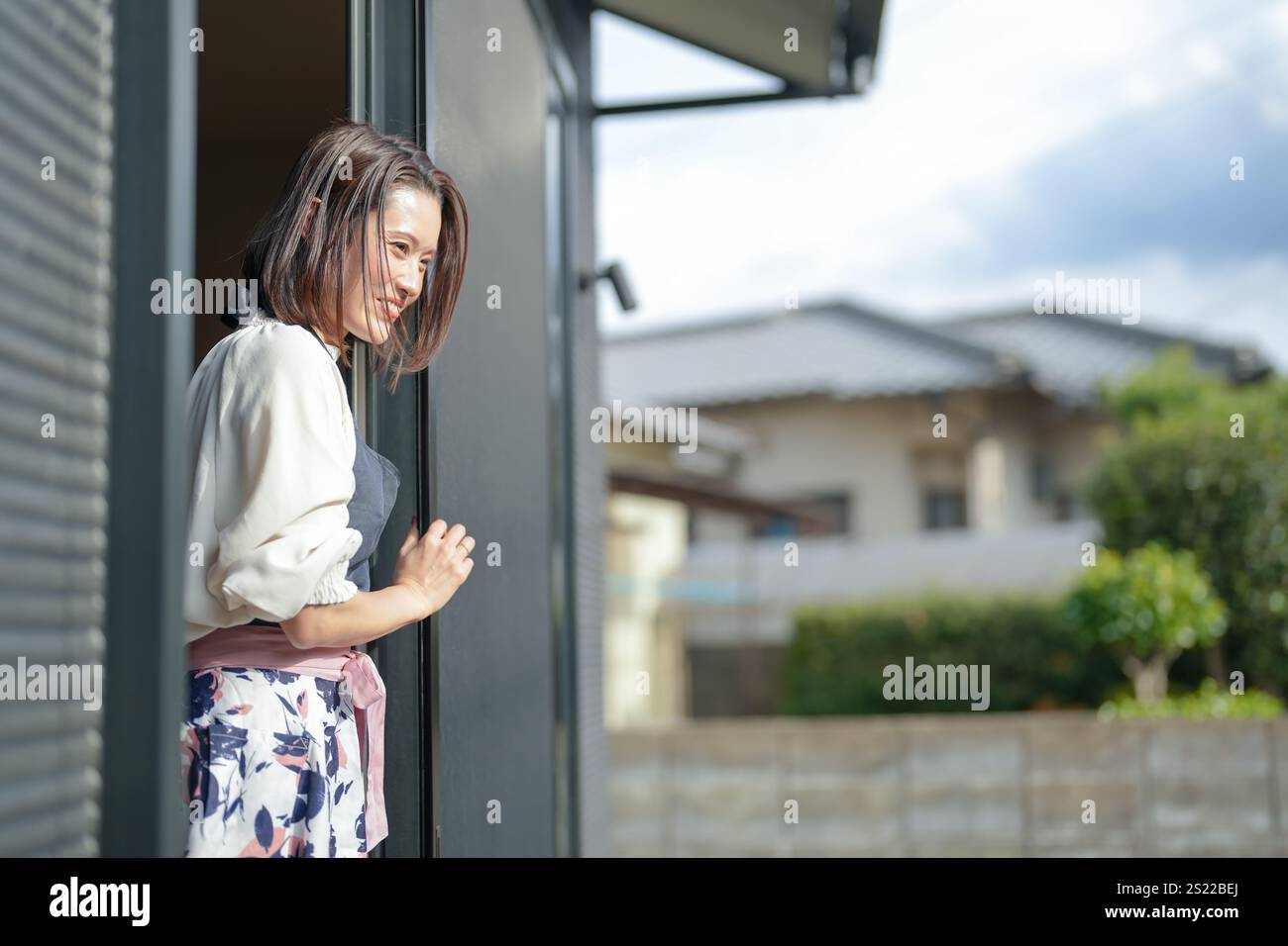 A Japanese woman in her 30s extends her body out of the window of her ...