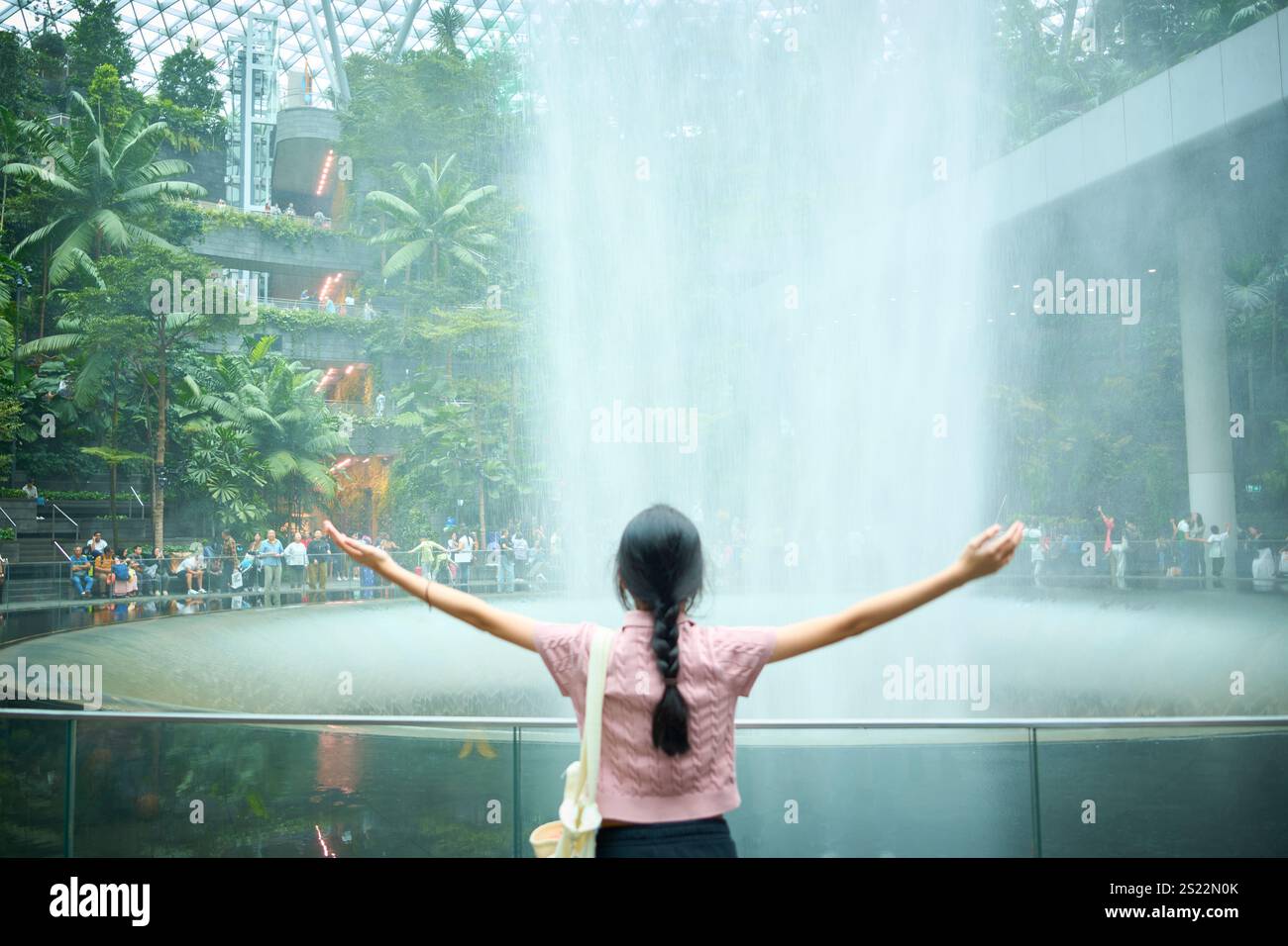 Young woman with open arms enjoying the rain vortex waterfall inside ...