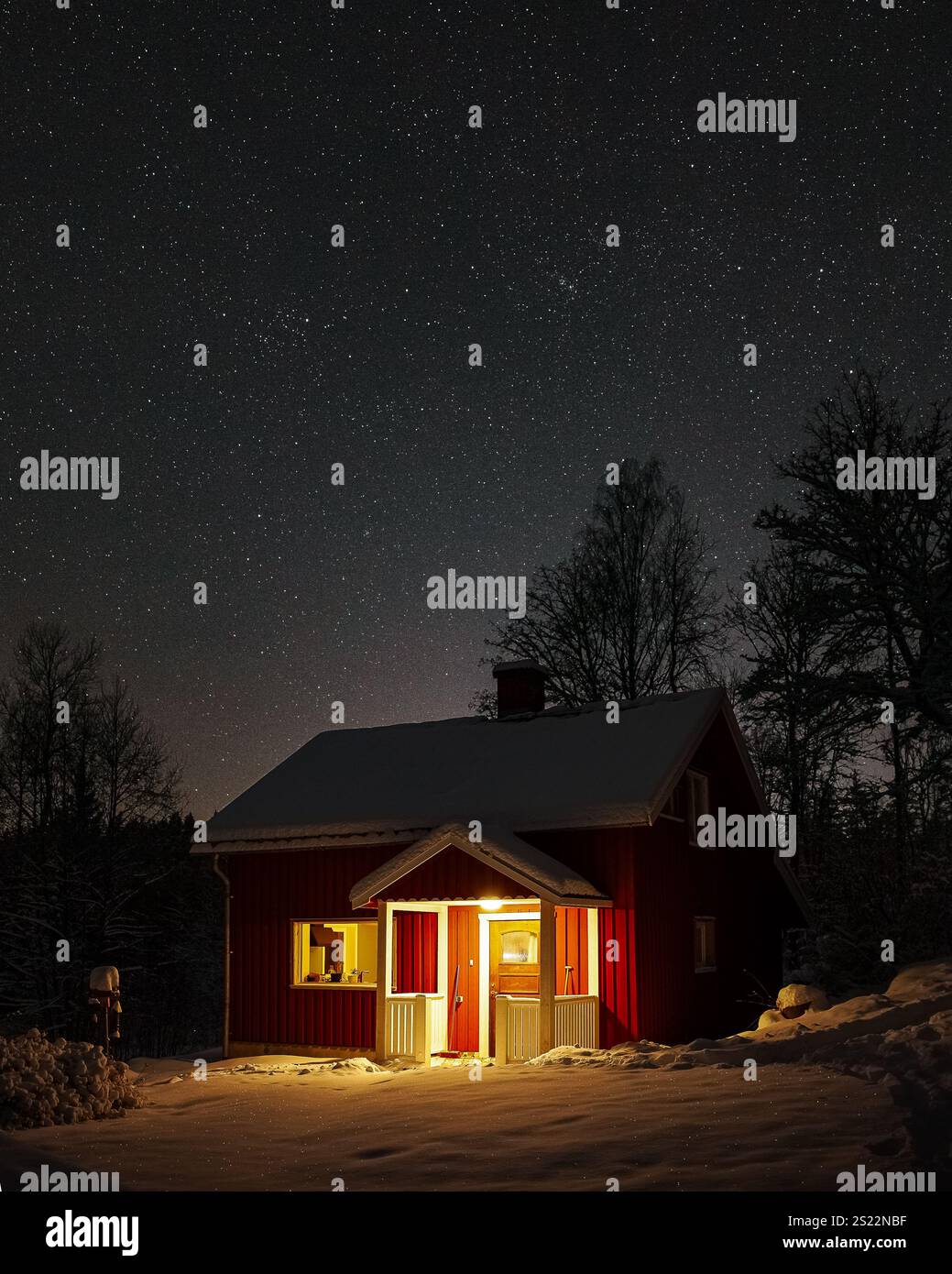 A traditional Swedish cottage beneath a starry night sky in winter ...