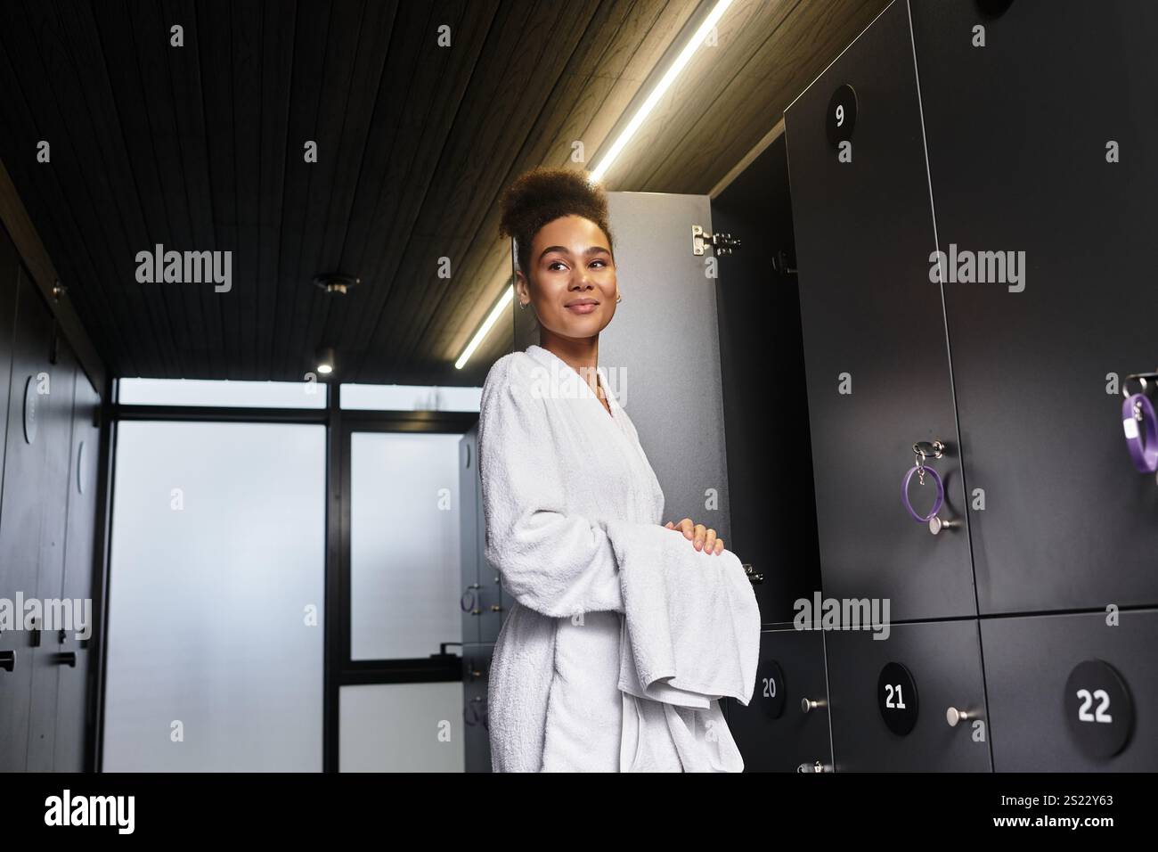 A beautiful young woman in a spa robe smiles while welcoming relaxation ...