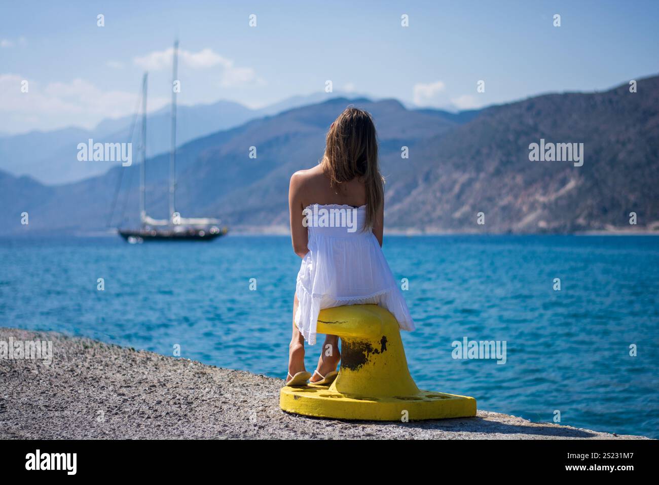 the woman in the white dress sitting on the pier waits for the ferry ...