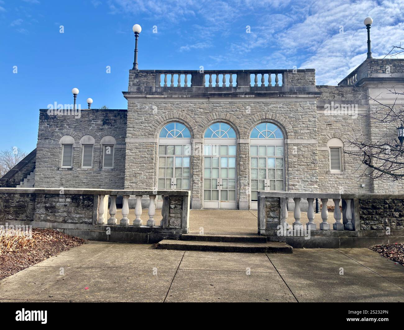 Historic stone building facade with arched windows and bright blue sky ...