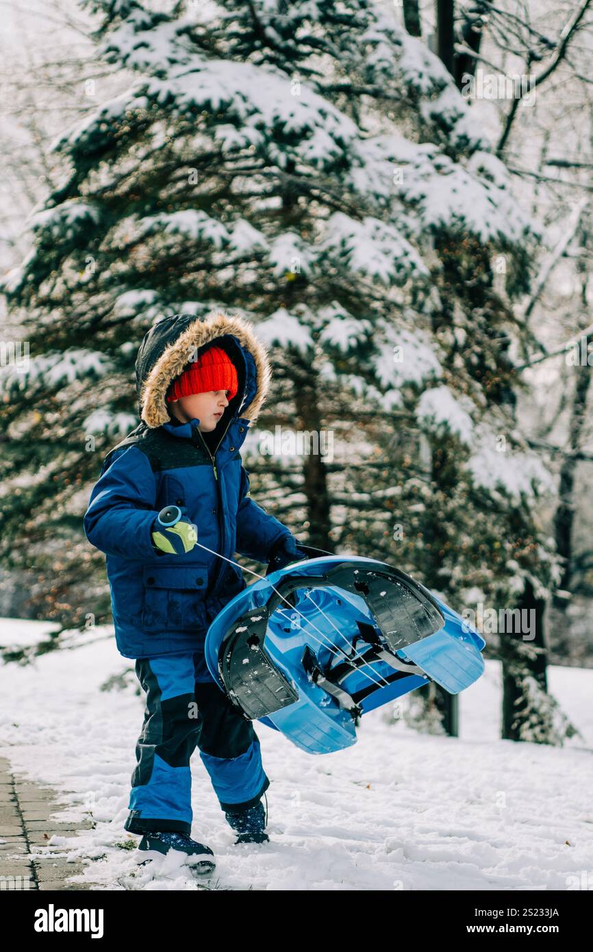 Child pulling sled in snowy yard Stock Photo - Alamy
