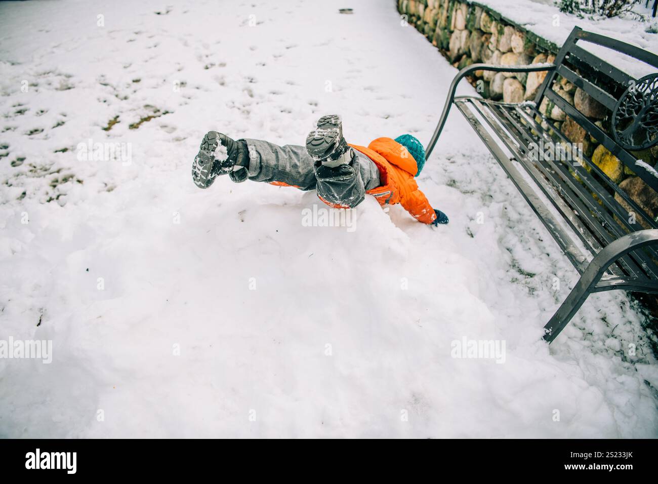 Child tumbling into snow pile near bench Stock Photo - Alamy