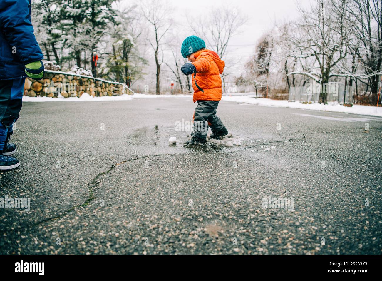 Child playing in a winter puddle on a snowy day Stock Photo - Alamy