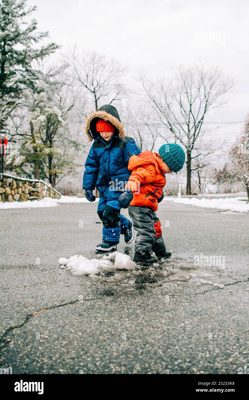 Kids playing in a snow puddle outdoors Stock Photo - Alamy