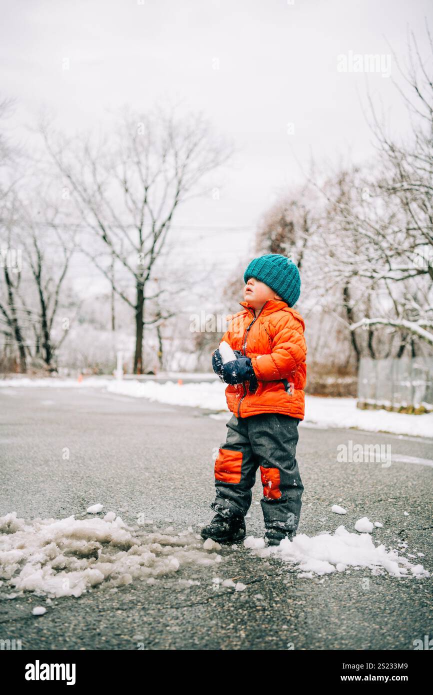 Young child exploring snow with curiosity on a wintery street Stock ...